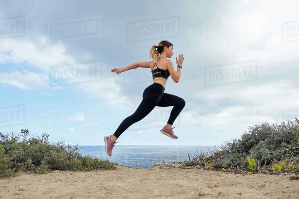 Side view full body slim determined female runner in black leggings and ...