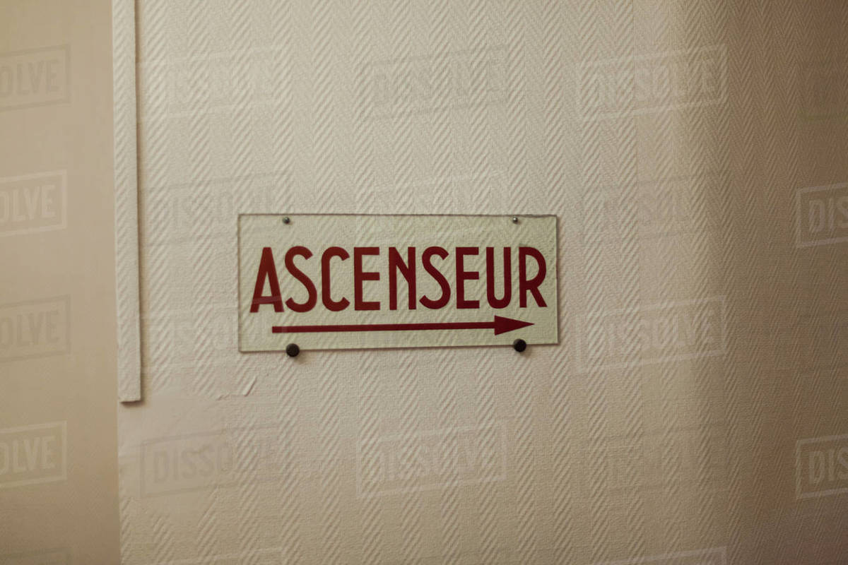 Glass signboard with French word ascenseur and arrow directing to right ...