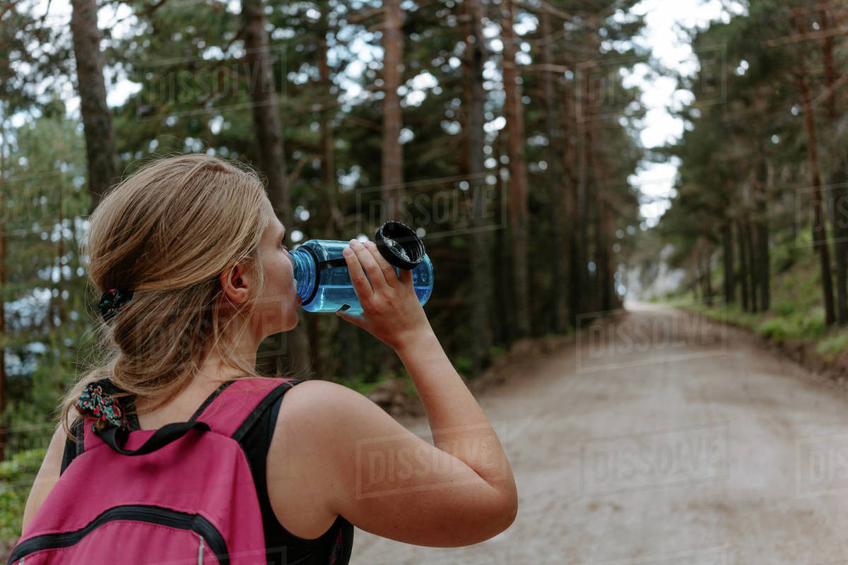 Back view of active young female backpacker standing on pathway among ...