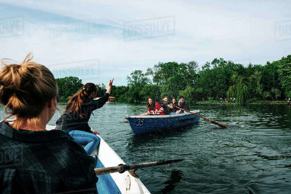 Group of young friends floating on boats along peaceful river while ...