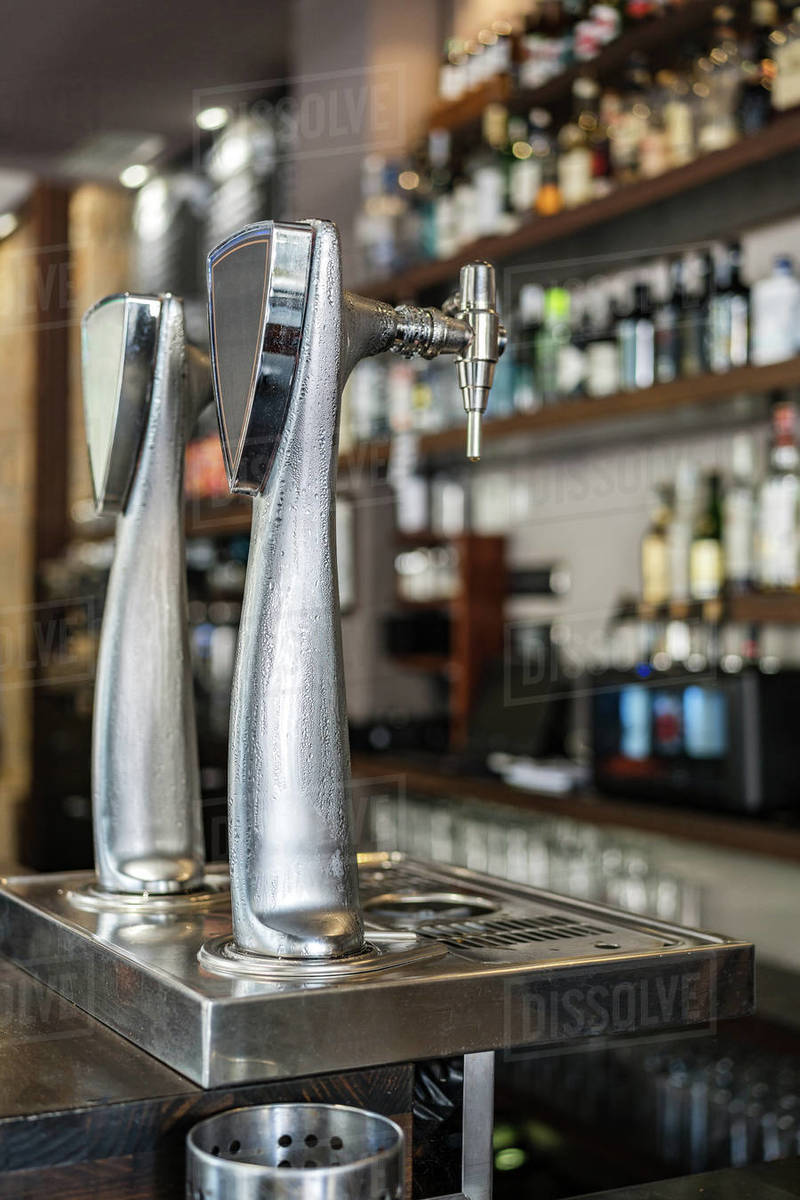 Metallic beer column placed on bar counter against shelves with ...