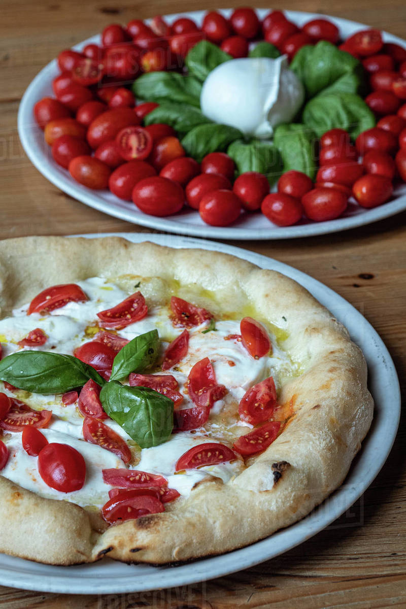 Round dish with yummy Pizza Margherita decorated with basil and dish ...