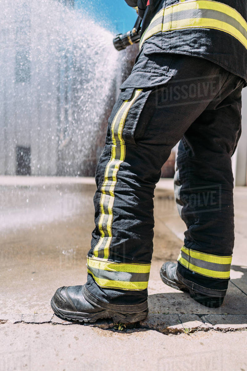 Side view of anonymous fireman in uniform and protective helmet using ...