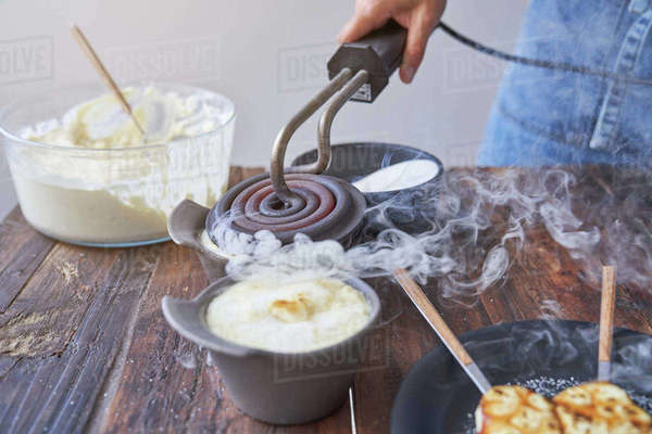 Crop view of anonymous woman burning delicious creme brulee with iron ...