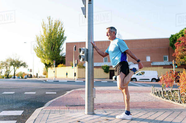 Retired senior man athlete stretching leg - Stock Photo - Dissolve
