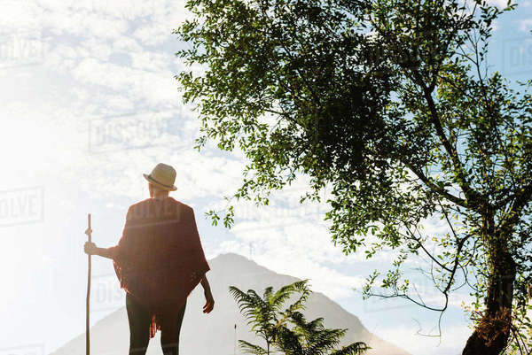 Back view of unrecognizable wanderer with wooden staff enjoying sunrise ...