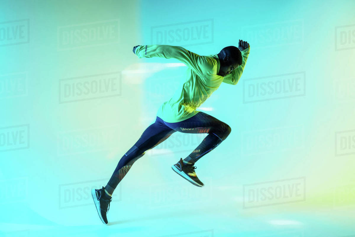 Full body side view of young African American male runner in colorful ...