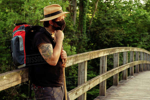 Side view of unrecognizable male wanderer in mask with backpack and ...