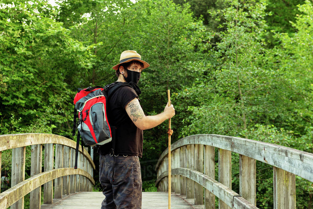 Side view of unrecognizable male wanderer in mask with backpack and ...