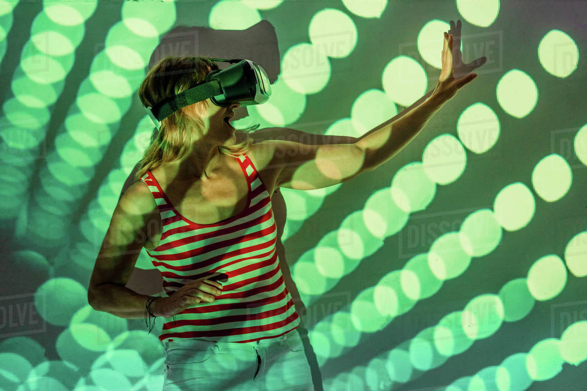 Unrecognizable young female in casual wear and VR headset getting new ...