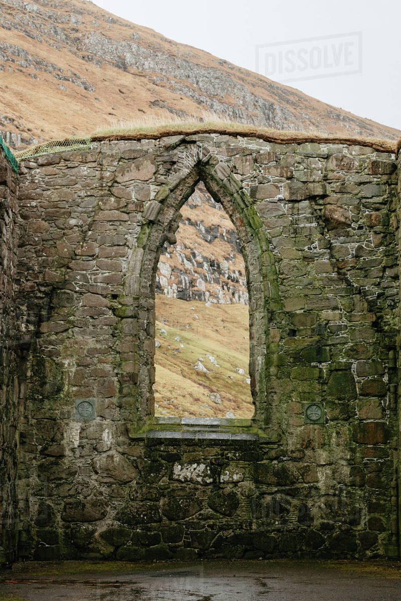Detail of aged stone building with arched window on background of ...