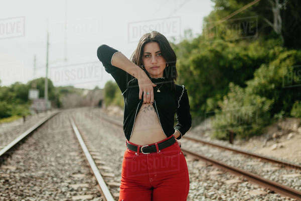 Pretty young woman in stylish outfit lifting sweater to show mountains ...