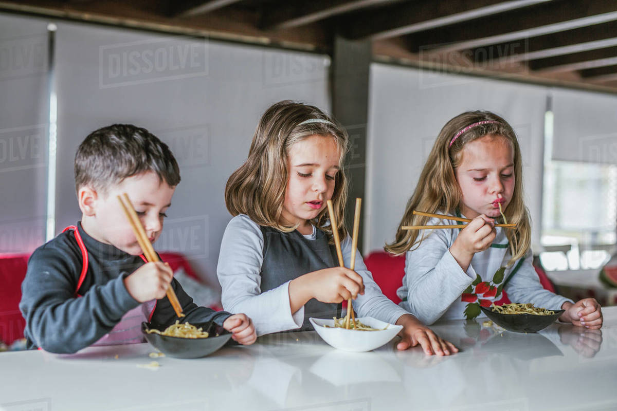 Boy and two girls eating tasty noodles with vegetarian cutlets and ...