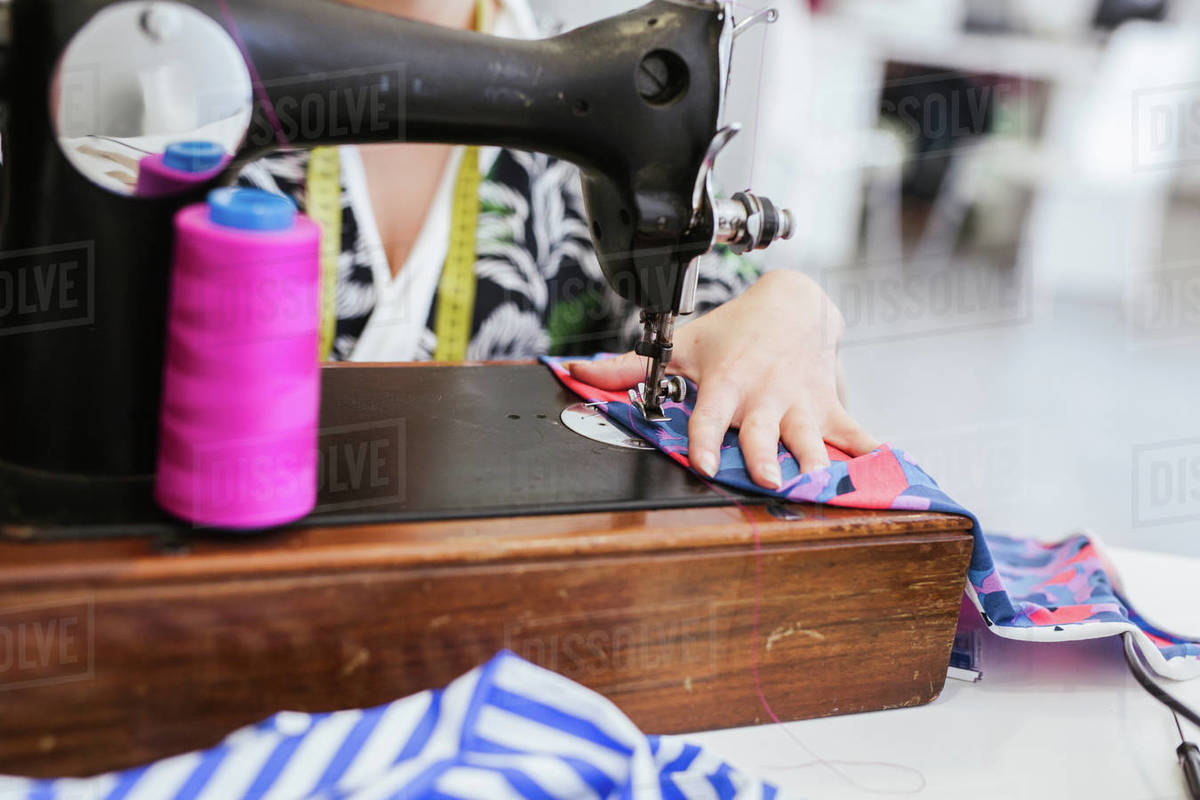 Teenage girl student practicing sewing on modern machine in cozy ...