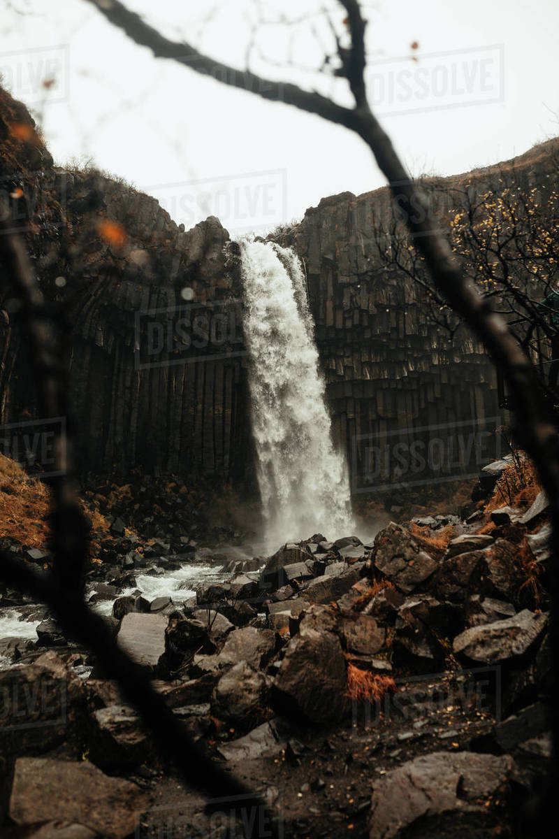 Picturesque view of amazing waterfall and rough cliff on gray day in ...