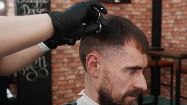 Hairstylist quickly cutting male hair by scissors in barber salon ...