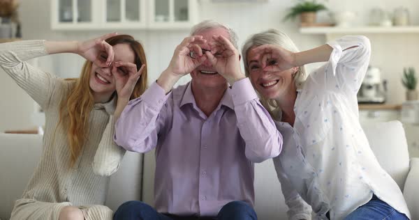 Family staring at camera through joined fingers showing eyeglasses ...