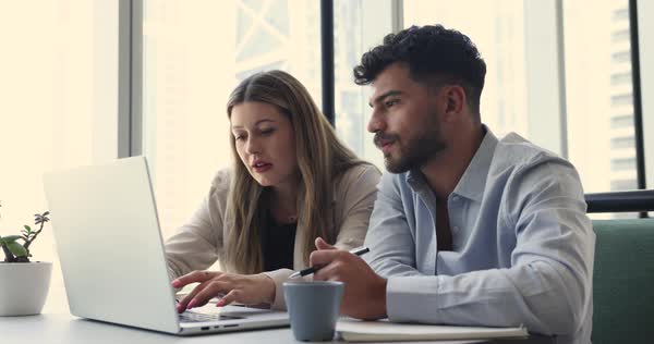 Two multiethnic office employees, coworkers working together using ...