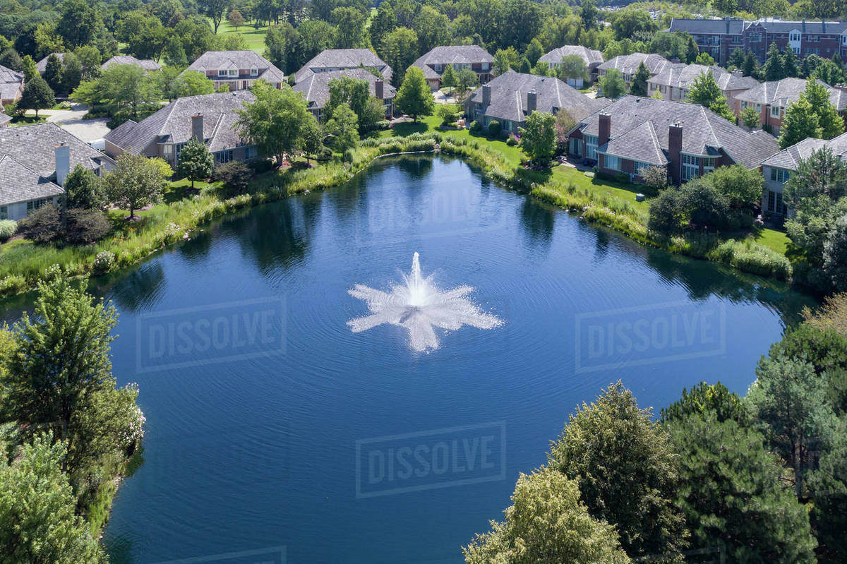 Aerial view of a luxury townhouse complex surrounded by a pond in a ...