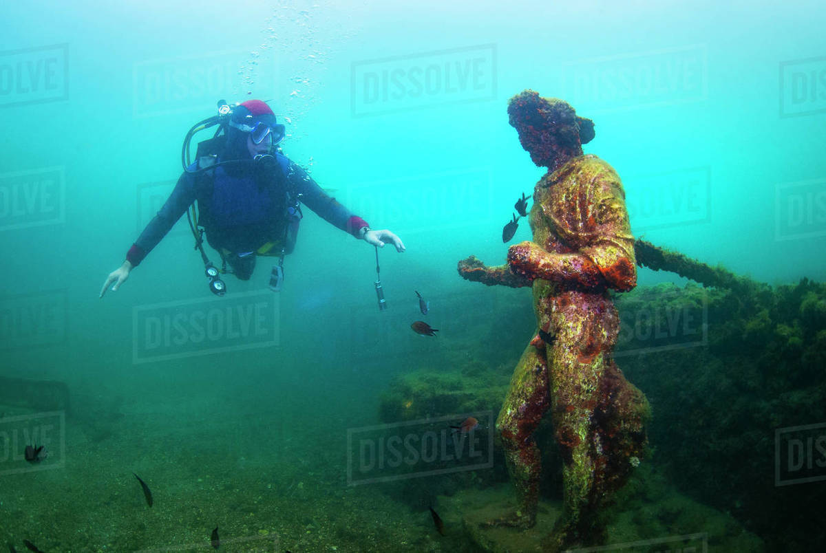 Scuba diver swimming by the submerged statue of Greek God Dionysus ...