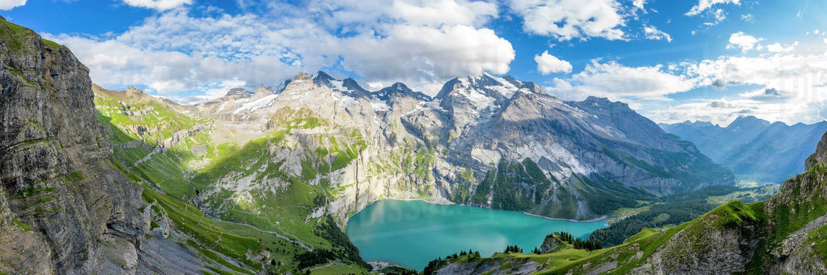 Aerial panoramic of Oeschinensee lake surrounded by woods in summer ...
