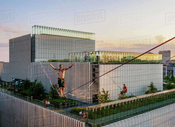 Man highlining with Centre for the Meeting of Cultures Building in the ...