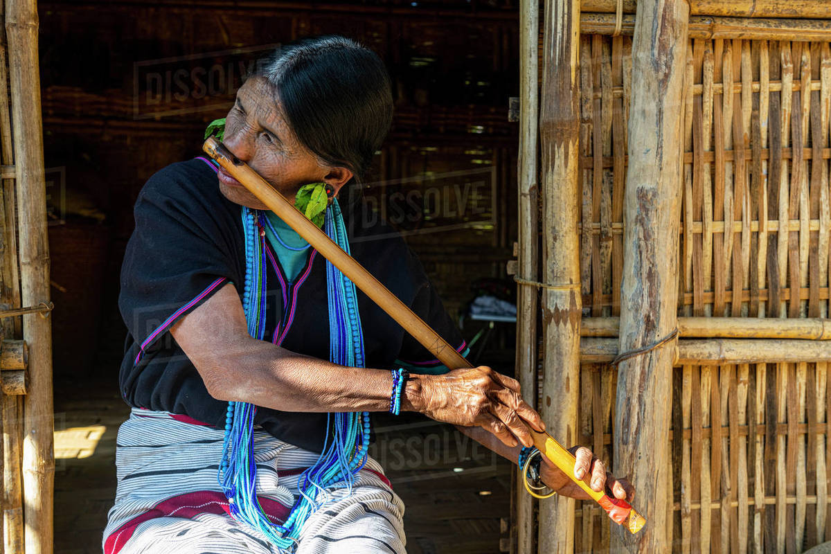 Chin woman with spiderweb tattoo blowing a flute with her nose ...