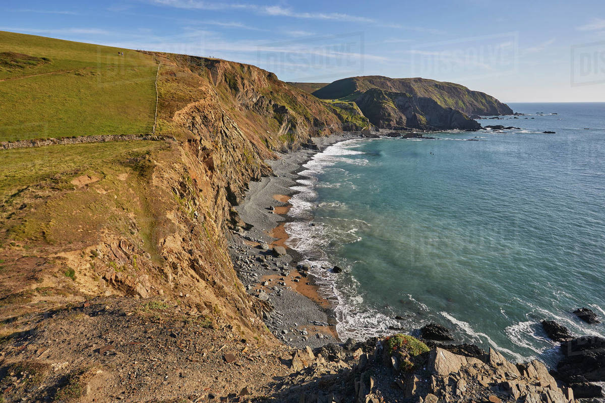 Cliffs along Devon's Atlantic coast bathed in late afternoon sunlight ...