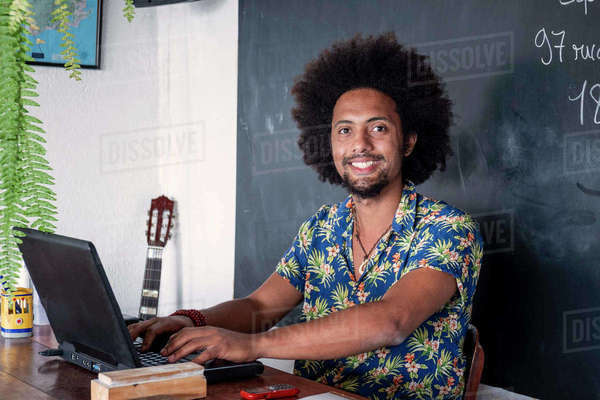 A Latin American man of African descent with Afro hair smiling to ...
