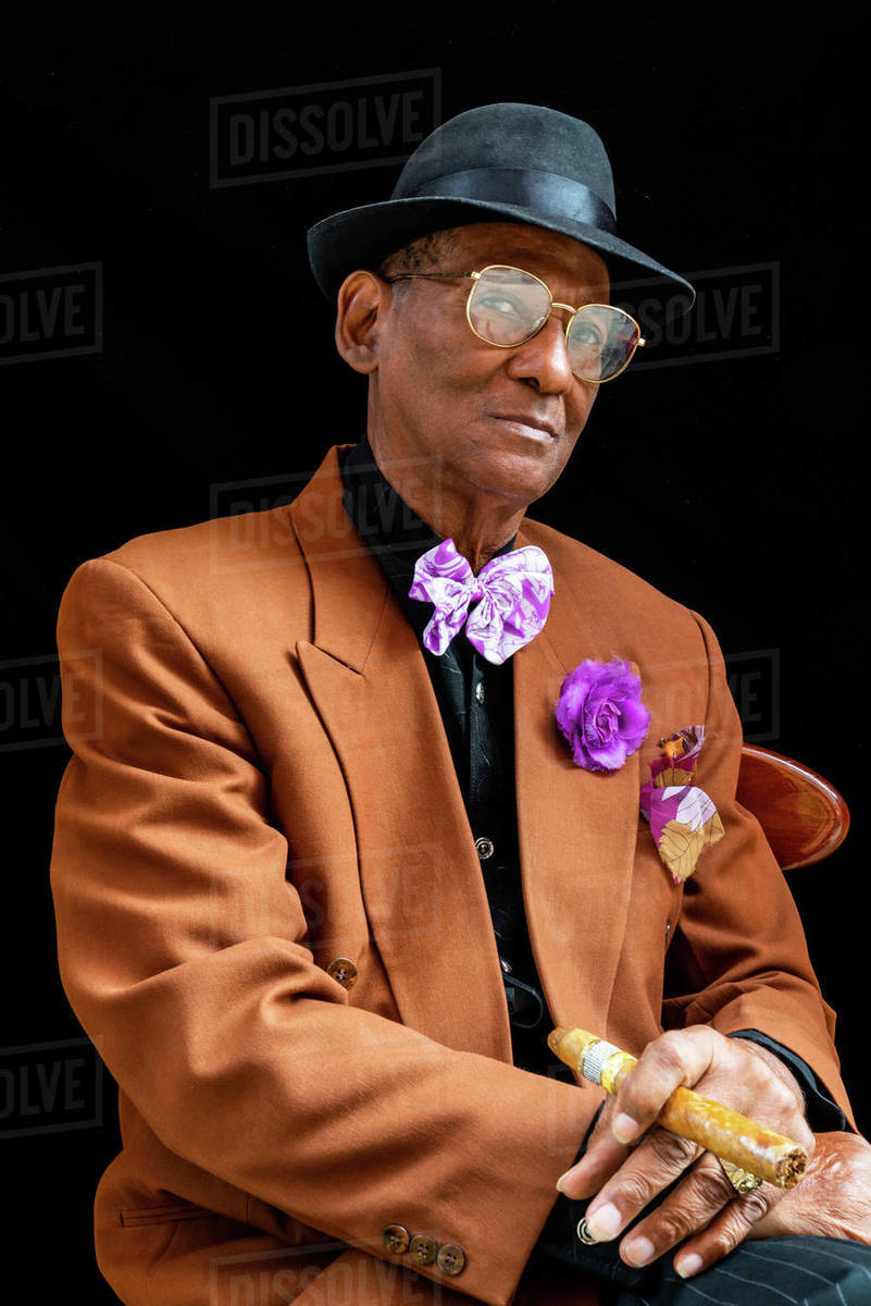 Man seated dressed as 1950s dandy or gangster with fedora hat and big ...