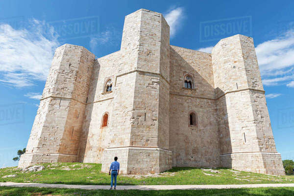 Man admires the octagonal castle of Castel del Monte in a clear sunny ...