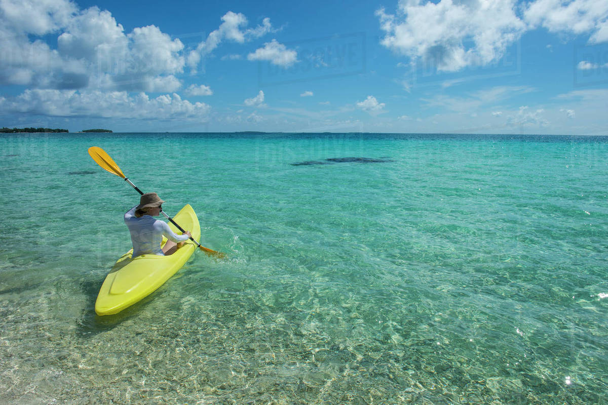 Woman kayaking in the turquoise waters of Tikehau, Tuamotus, French ...