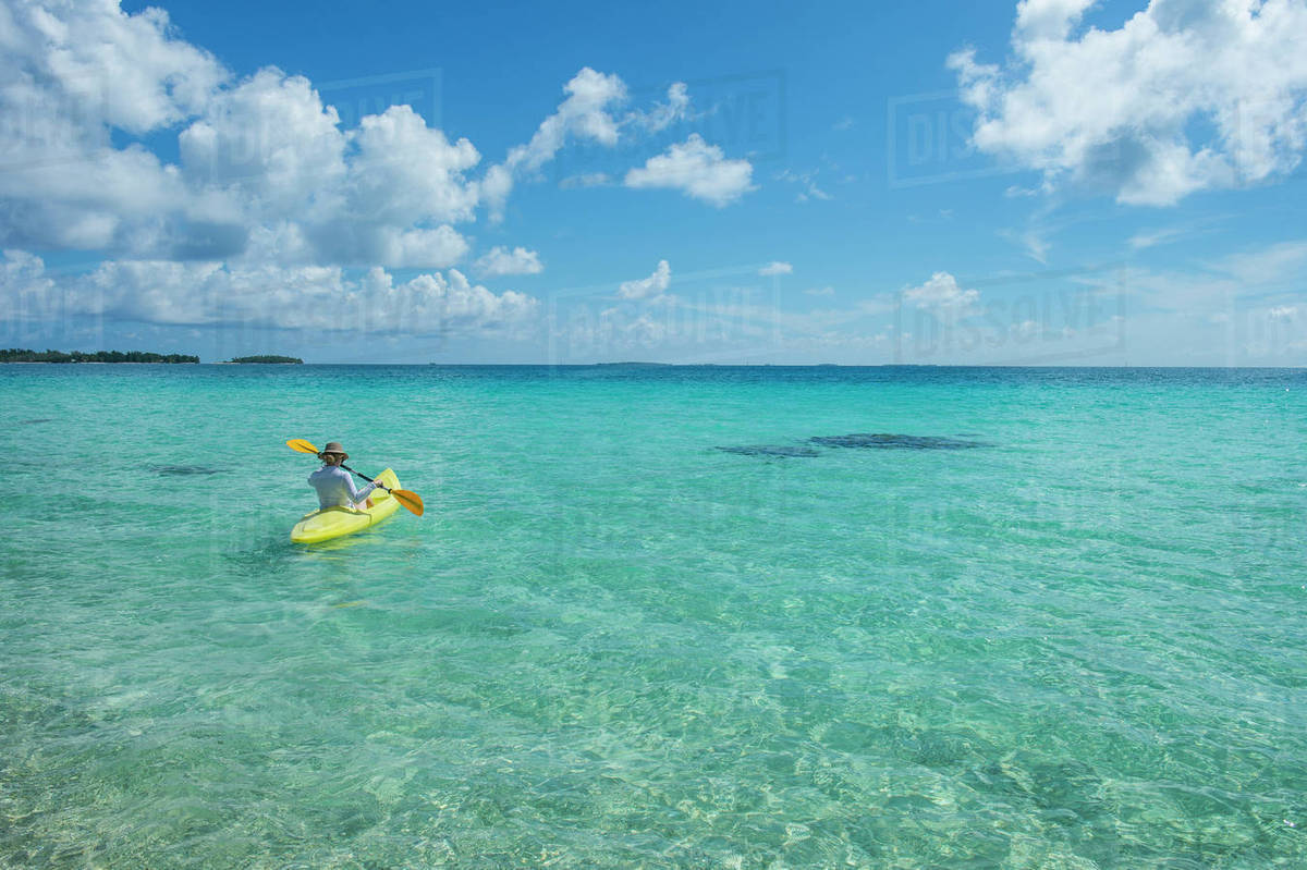 Woman kayaking in the turquoise waters of Tikehau, Tuamotus, French ...