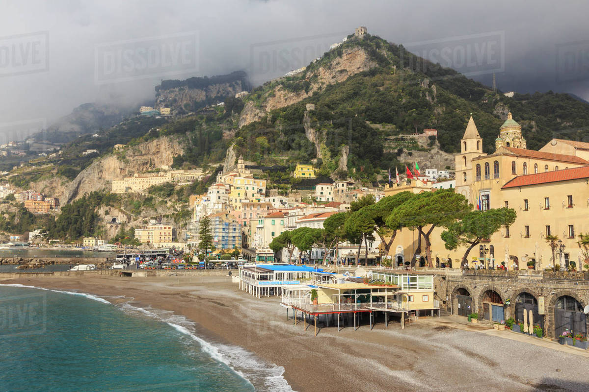 Amalfi waterfront in spring sun, with mist shrouded mountains, Amalfi ...