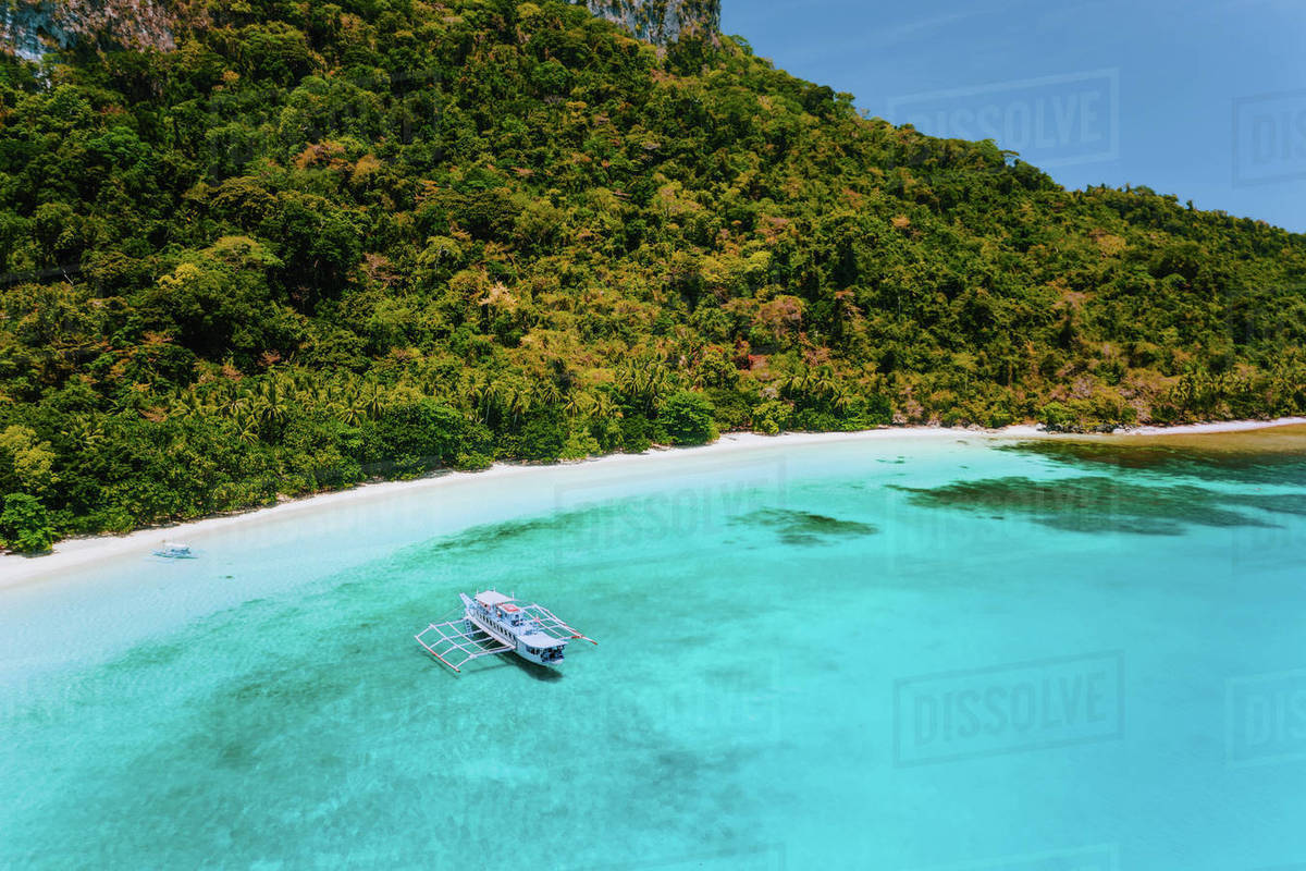 Aerial view of boat moored at secluded tropical beach with white sand ...