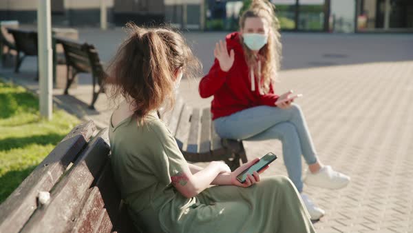 Two familiar young girls greet each other by waving at hand at a safe ...