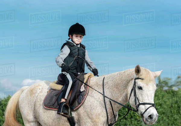 Boy horseback riding at ranch - Stock Photo - Dissolve