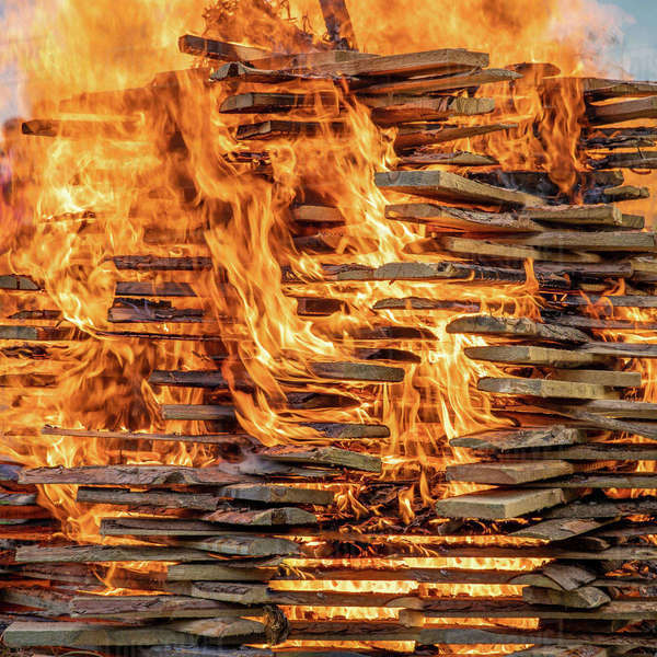 wooden boards burn with a large, flaming orange flame with traditional ...