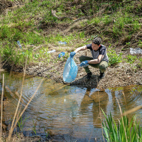 cleaning of plastic waste on the river bank by a volunteer. Helping ...