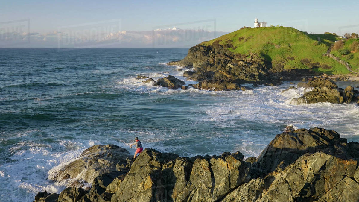 early morning shot of a fisherman rock fishing near tacking point ...