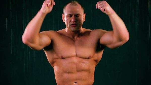 Bodybuilder stands under water jets, he gets into few poses with ...