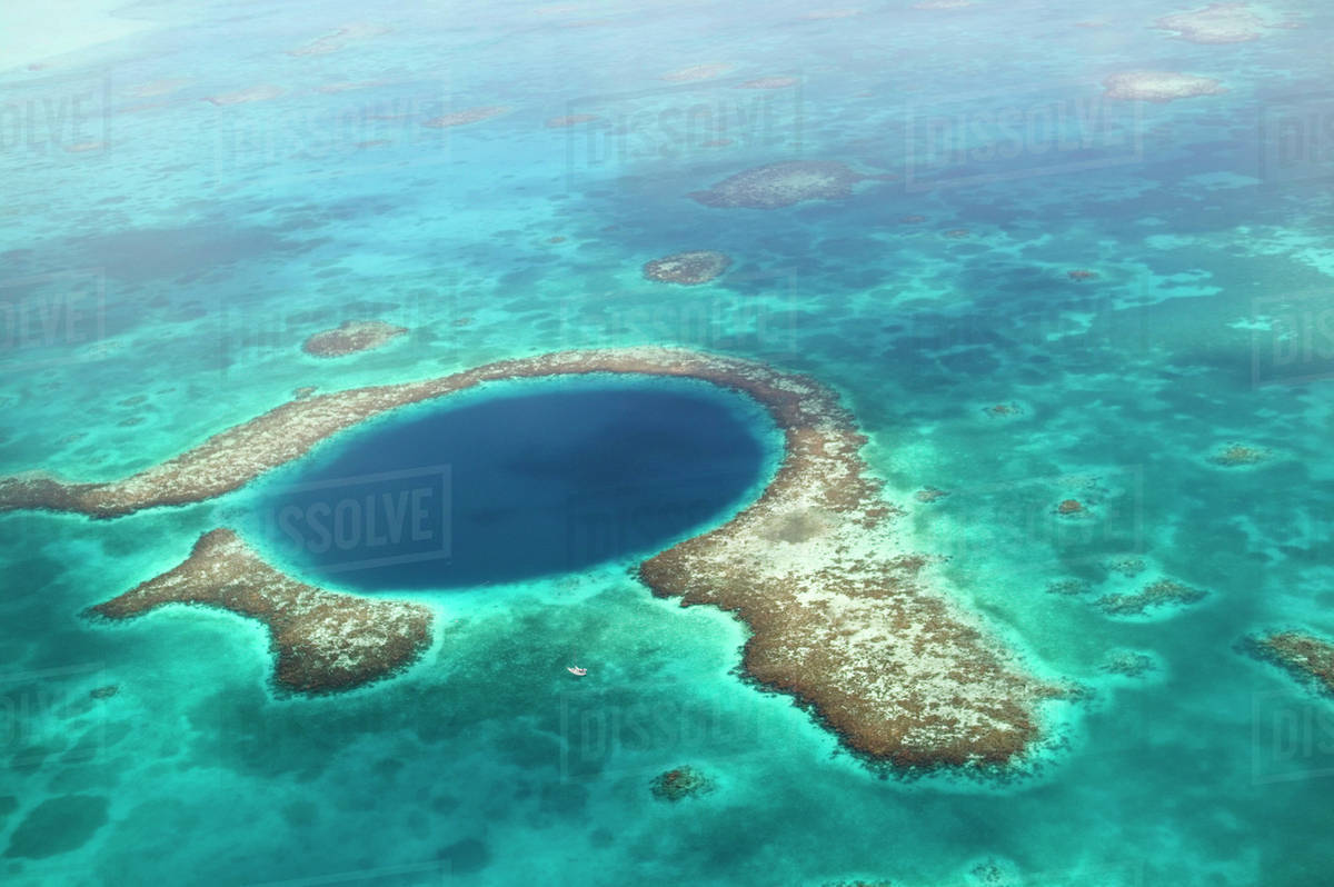 Aerial view of Blue Hole, sailboat anchored nearby, Lighthouse Atoll ...