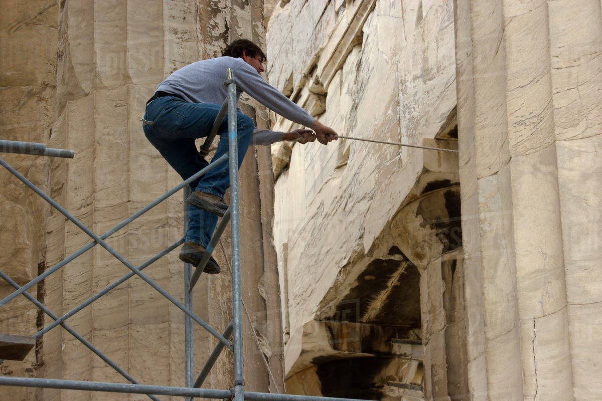 Greece, Athens, Acropolis. Man on scaffold at historic Parthenon ...