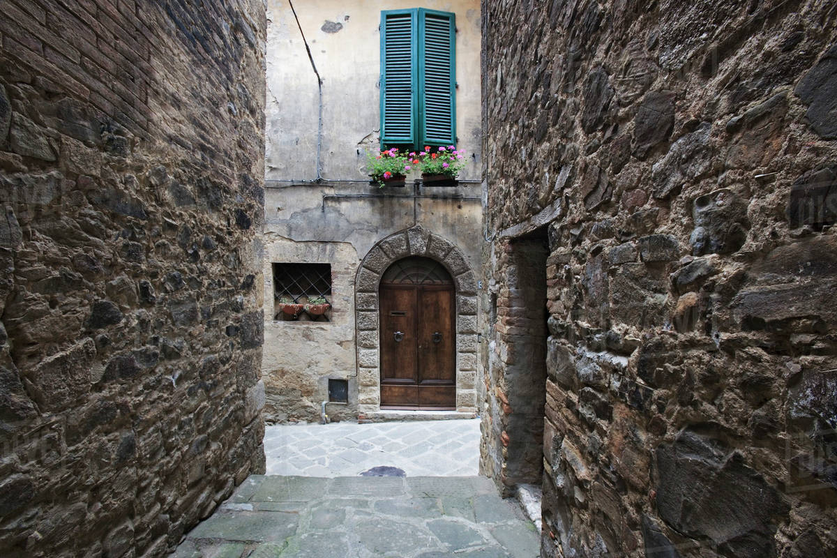 Italy, Petroio. Narrow walkway frame a doorway in a Tuscany village ...