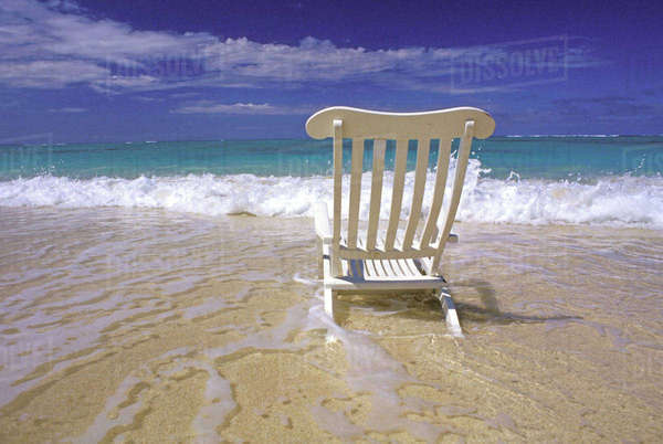 USA, Hawaiian Islands. Beach chair in surf - Stock Photo - Dissolve
