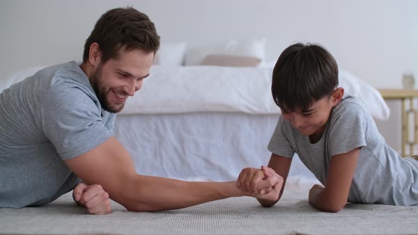 Dad and son are fighting with their hands lying on the floor of the ...