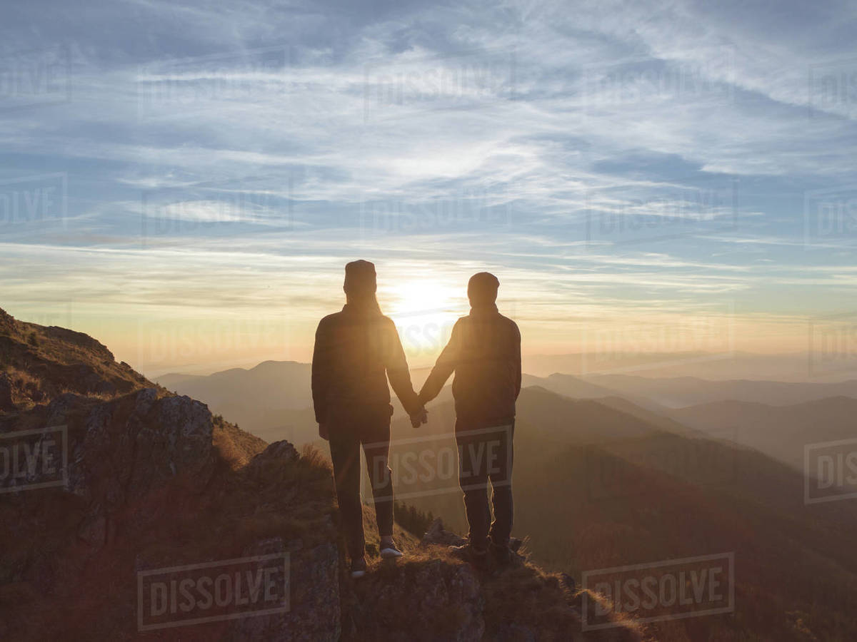 The couple standing on the mountain on the beautiful sunrise background ...