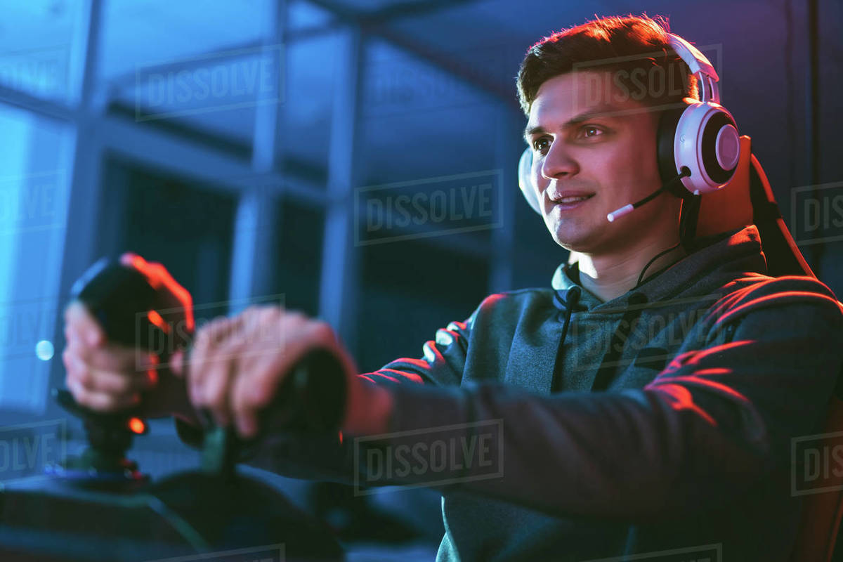 The gamer sitting at the table and playing video games in the neon room ...