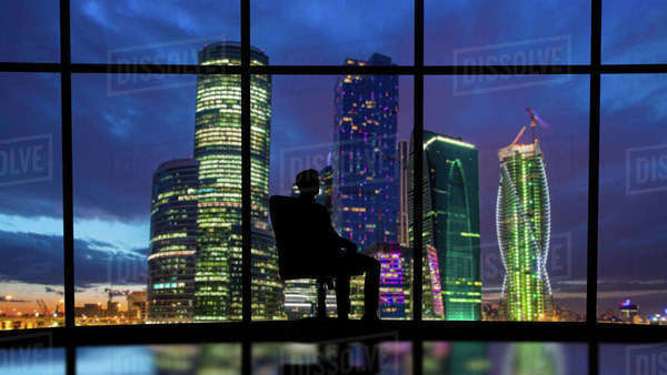 The business man sitting in the office near the window with a night ...