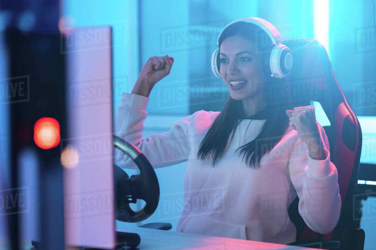 The beautiful gamer girl with headphones playing video games - Royalty ...